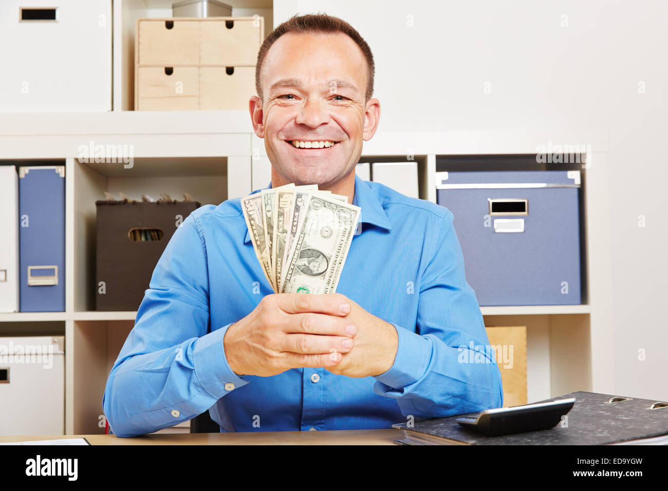 Happy business man holding fan of dollar money bills at his desk Stock ...