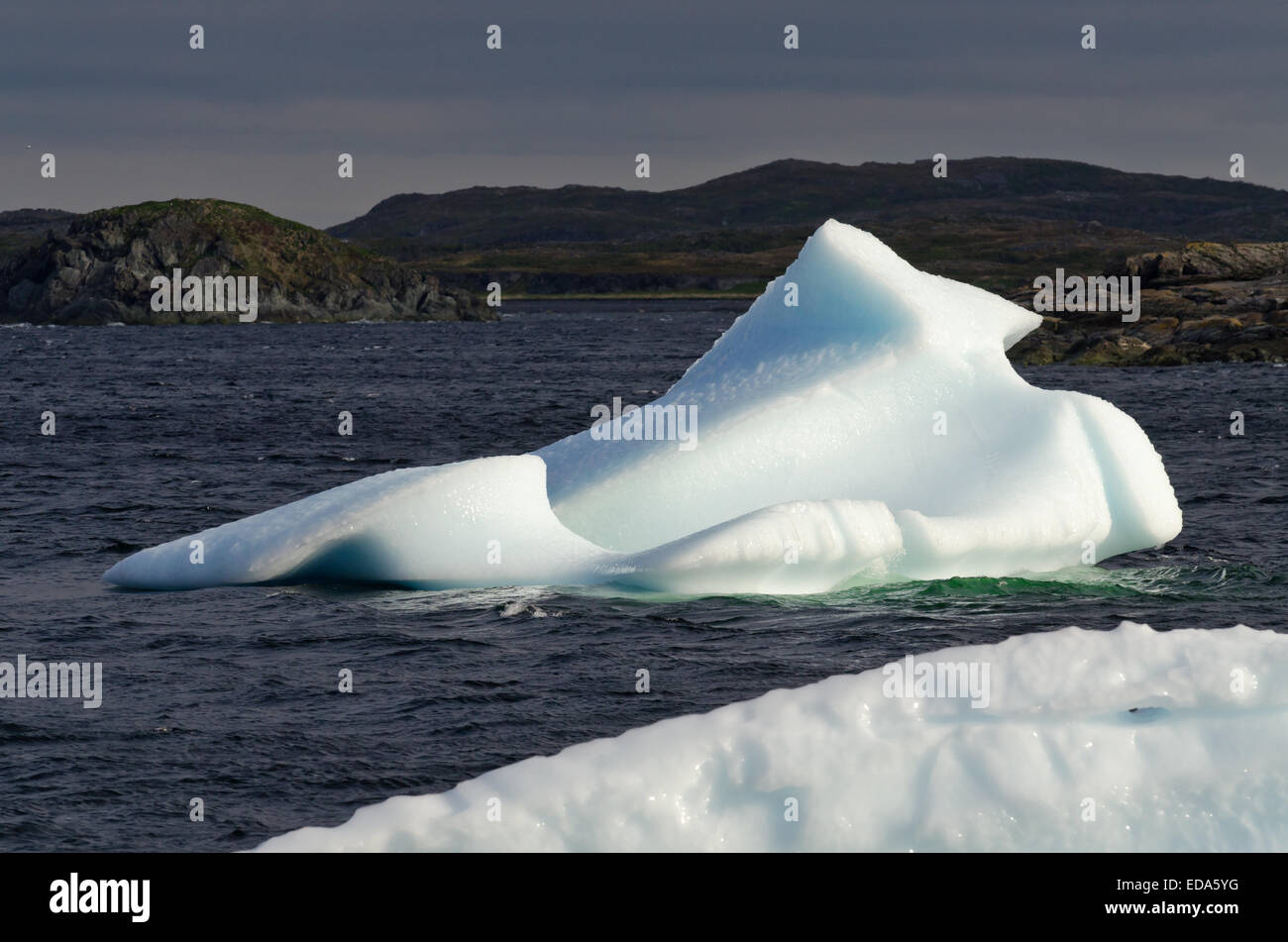 Bright white iceberg on dark water and rock background Stock Photo - Alamy