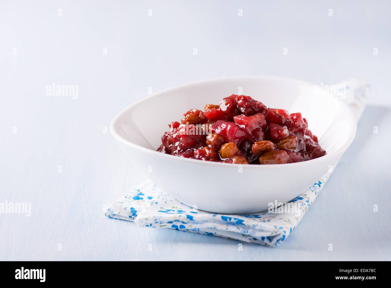 Pear cranberry relish in a white bowl over light blue background with ...