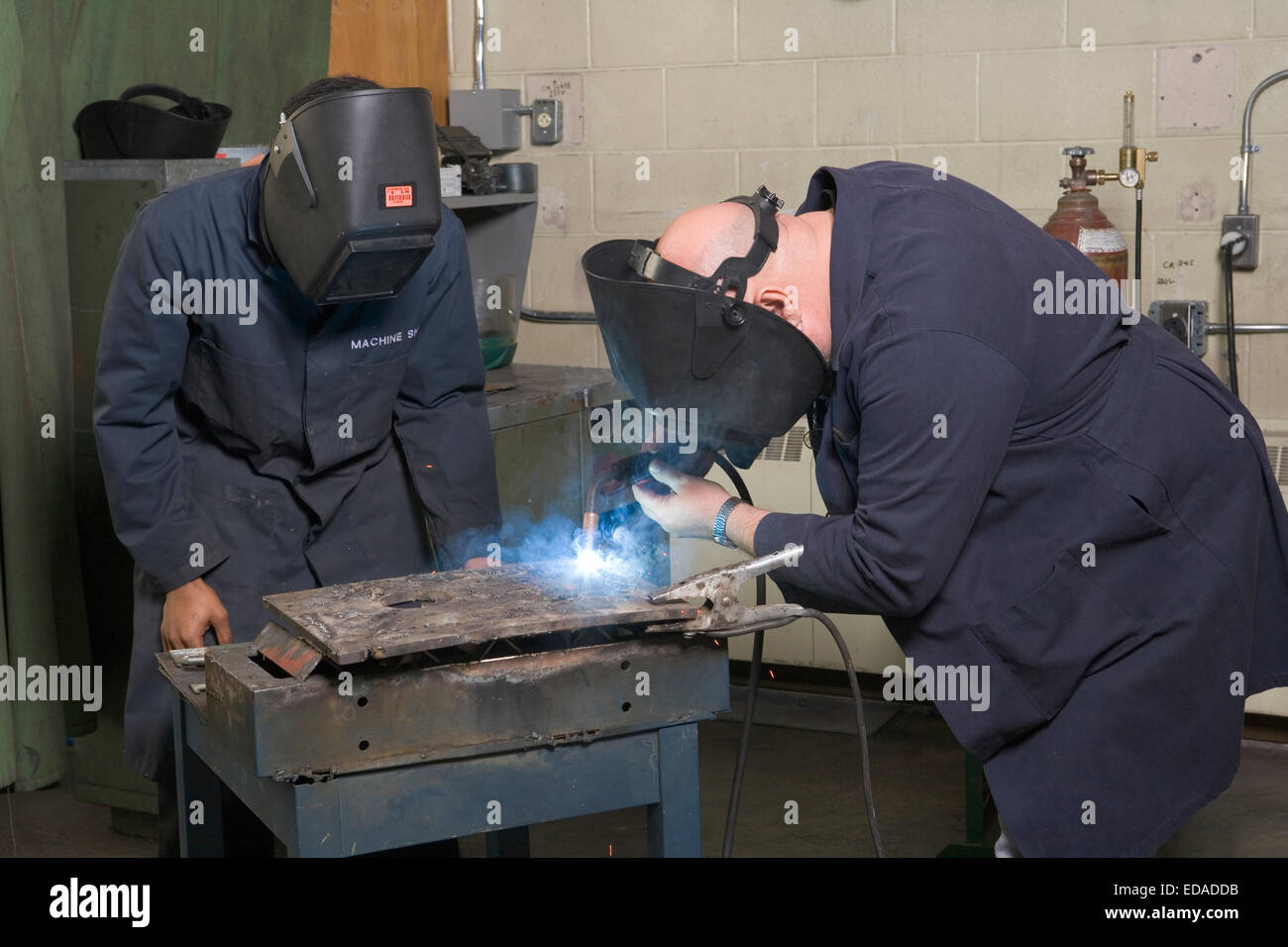 Teacher showing a student how to weld Stock Photo - Alamy