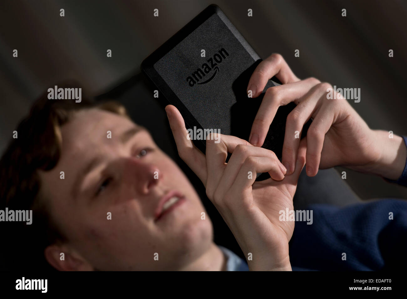 Young man male reads Amazon Kindle e book reader Stock Photo - Alamy