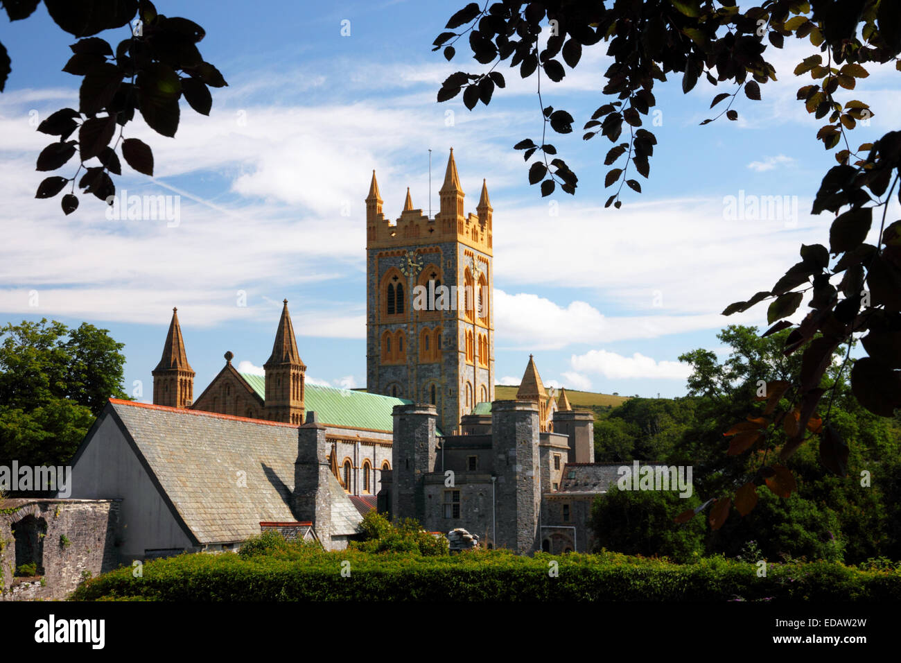 A large abbey built of golden stone with a tower framed by trees Stock ...
