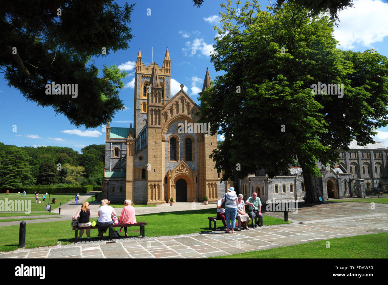 A large abbey built of golden stone with a tower and surrounded by ...