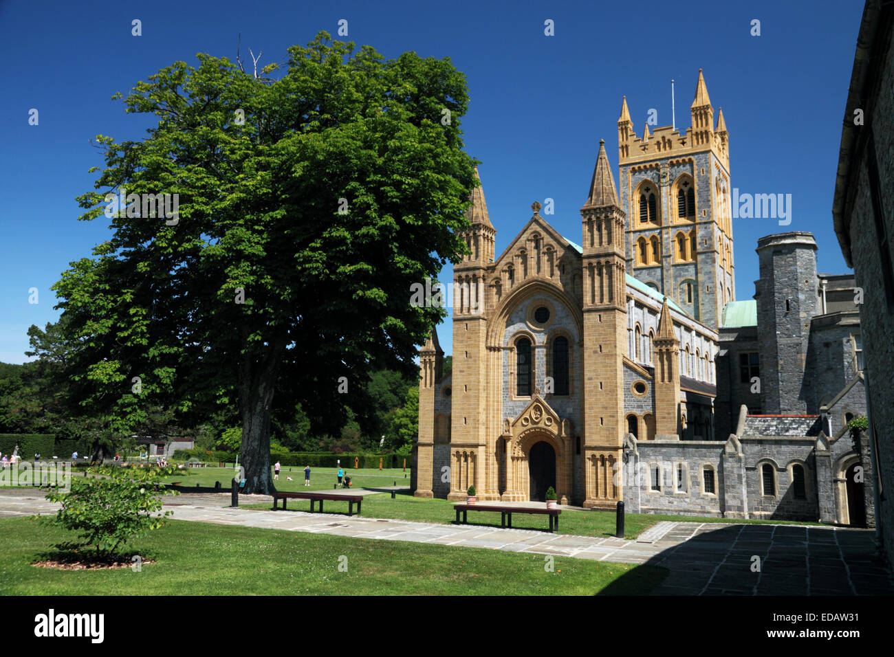 A large abbey built of golden stone with a tower and surrounded by ...