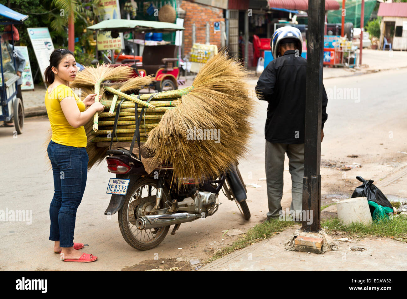 Woman buying a broom from a motorcycle broom seller, Siem Reap ...