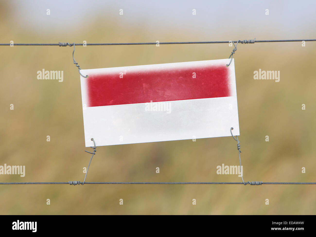 Border fence - Old plastic sign with a flag - Monaco Stock Photo - Alamy