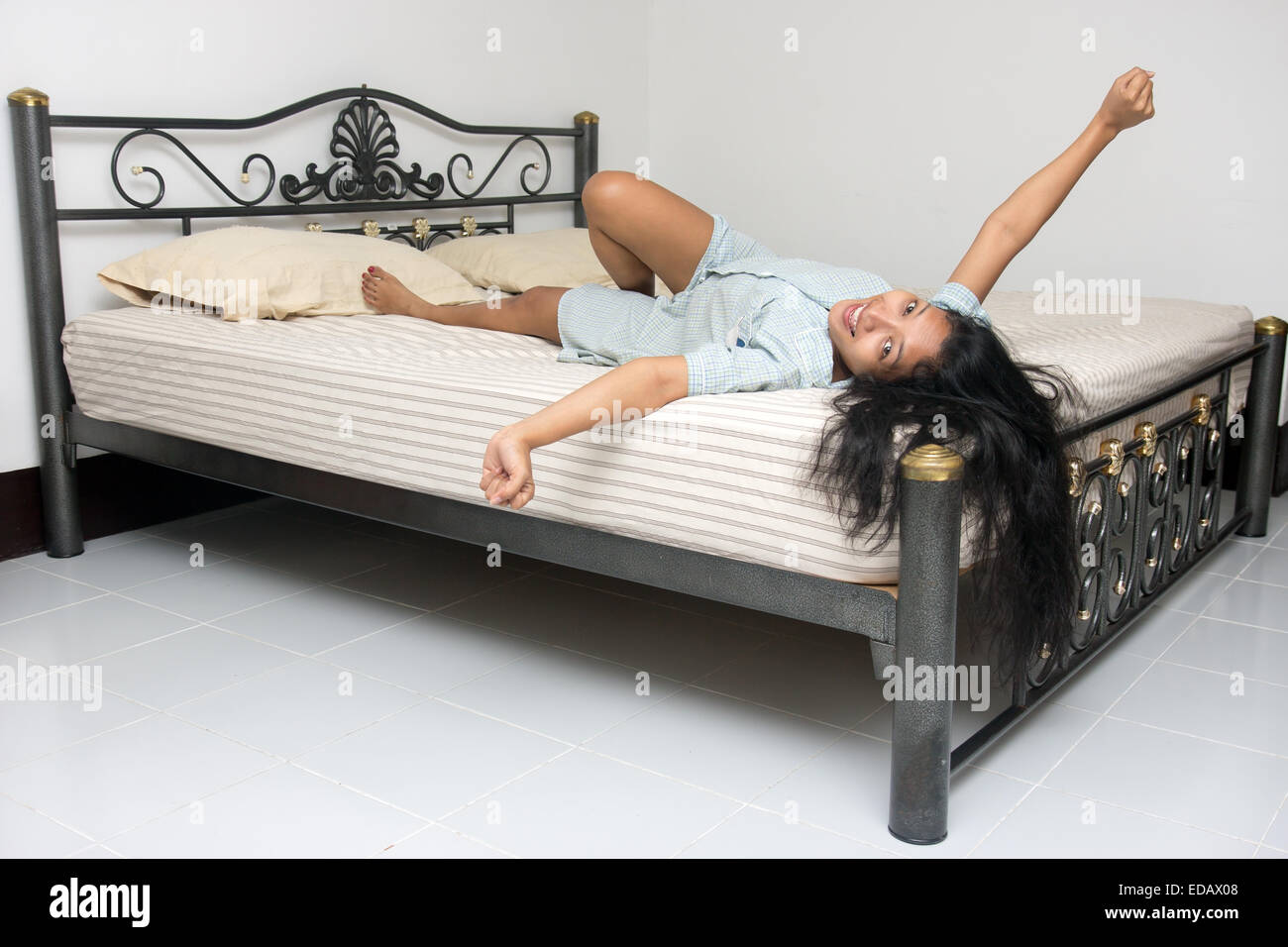 Young woman stretching in bed Stock Photo - Alamy