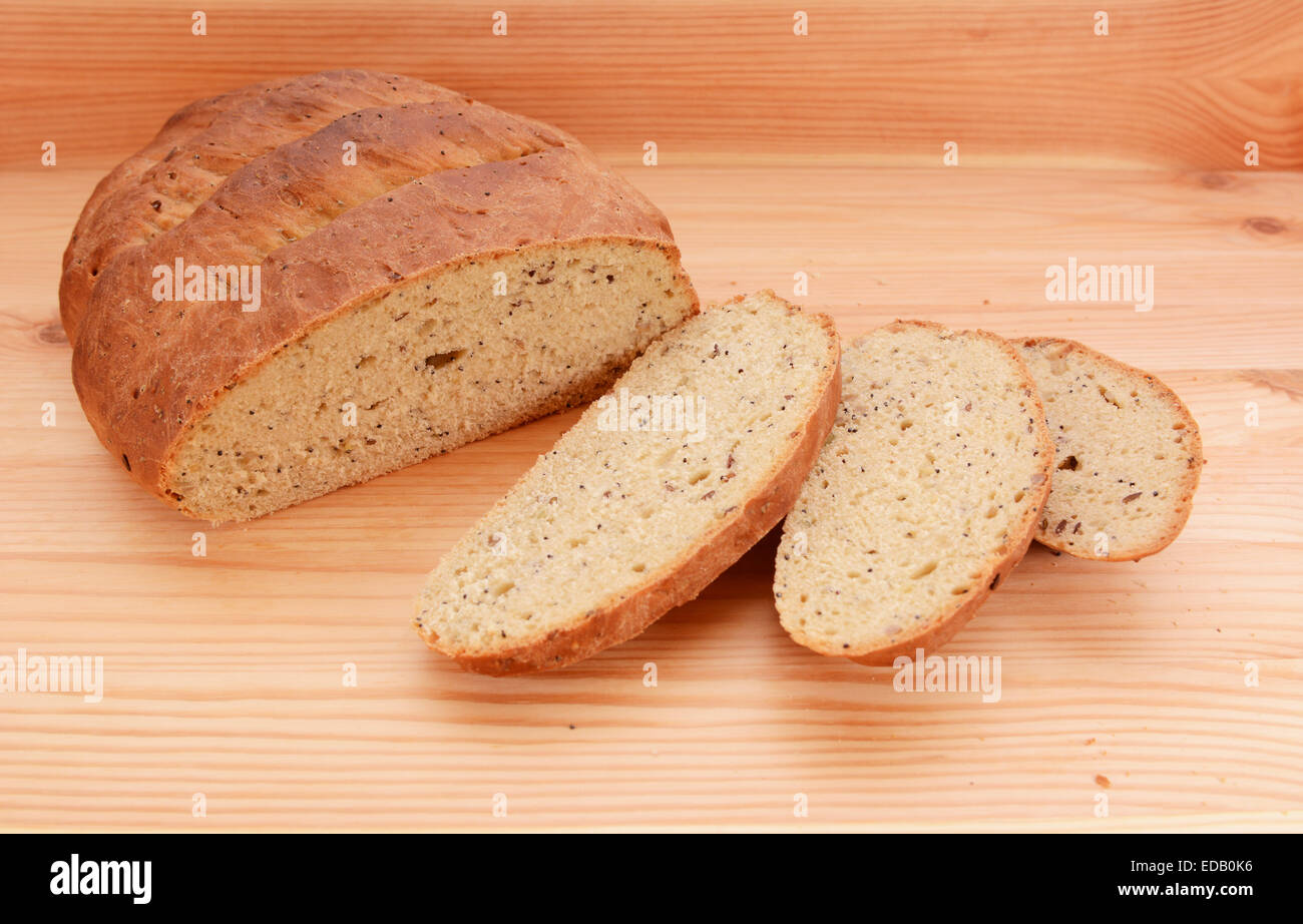 Three slices of fresh bread next to a new loaf of multi seed bread on a ...