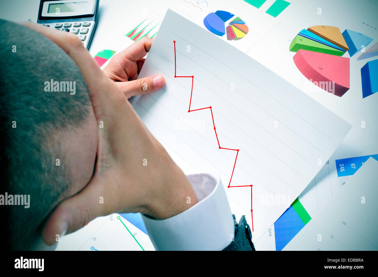 businessman in his office desk full of graphs and charts observing ...