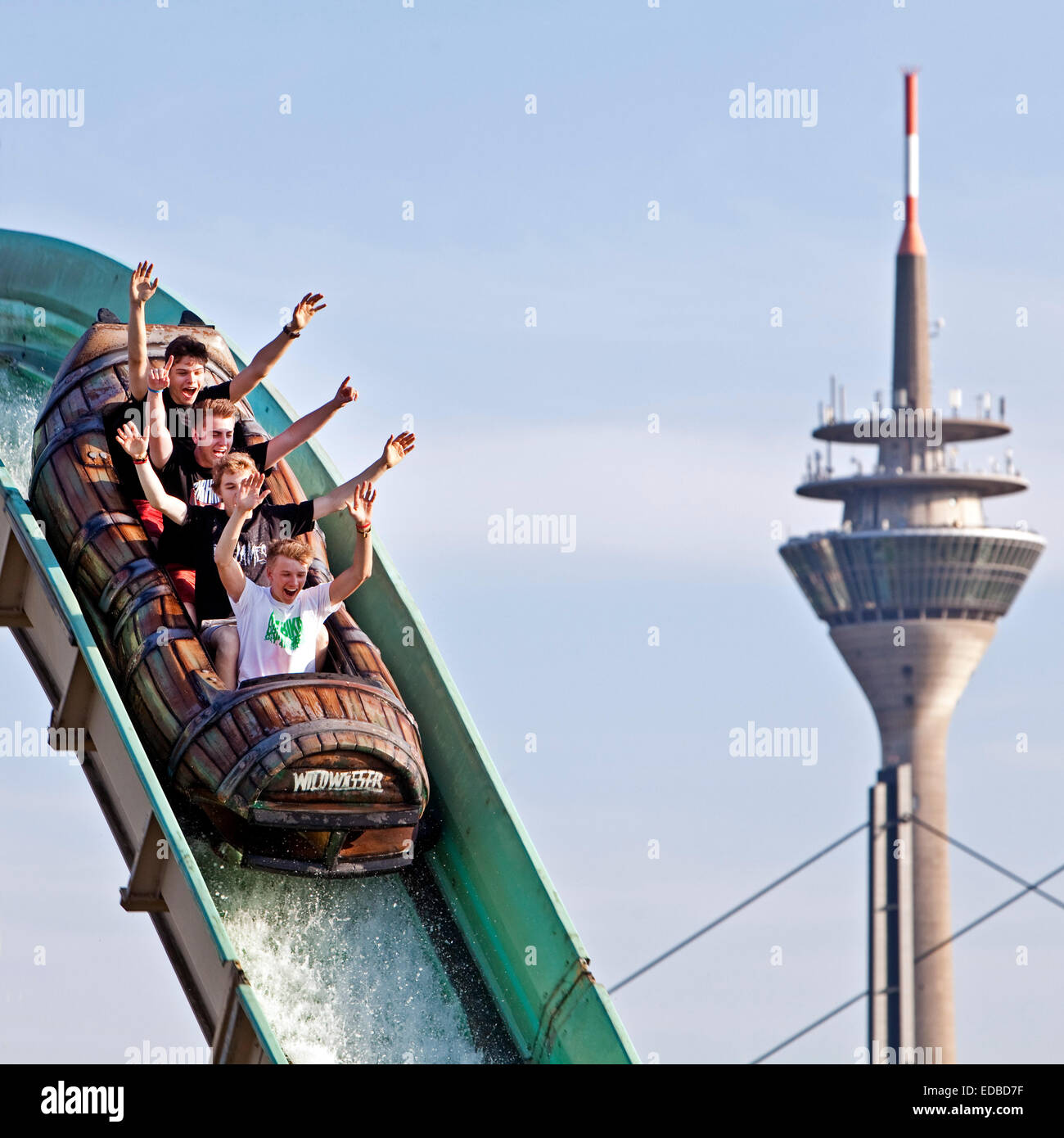 Four young men on the log flume in front of the Rhine Tower, Düsseldorf ...