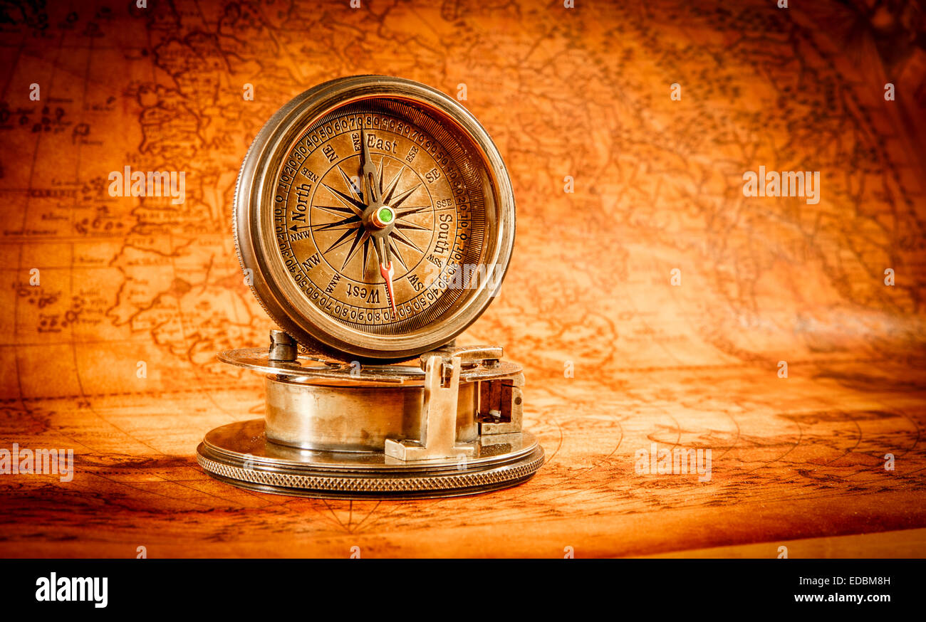 Vintage still life. Vintage compass lies on an ancient world map in ...