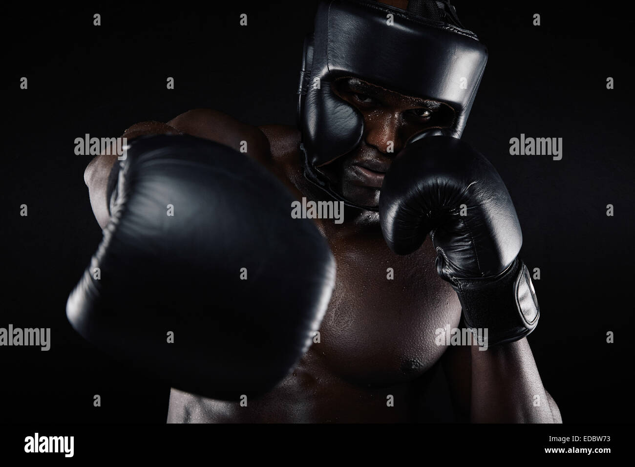 Portrait of African male practicing boxing looking at camera against ...