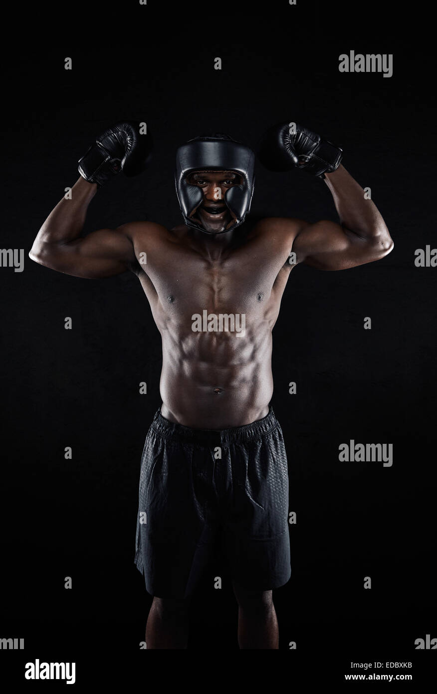 Portrait of happy young African boxing winner on black background ...