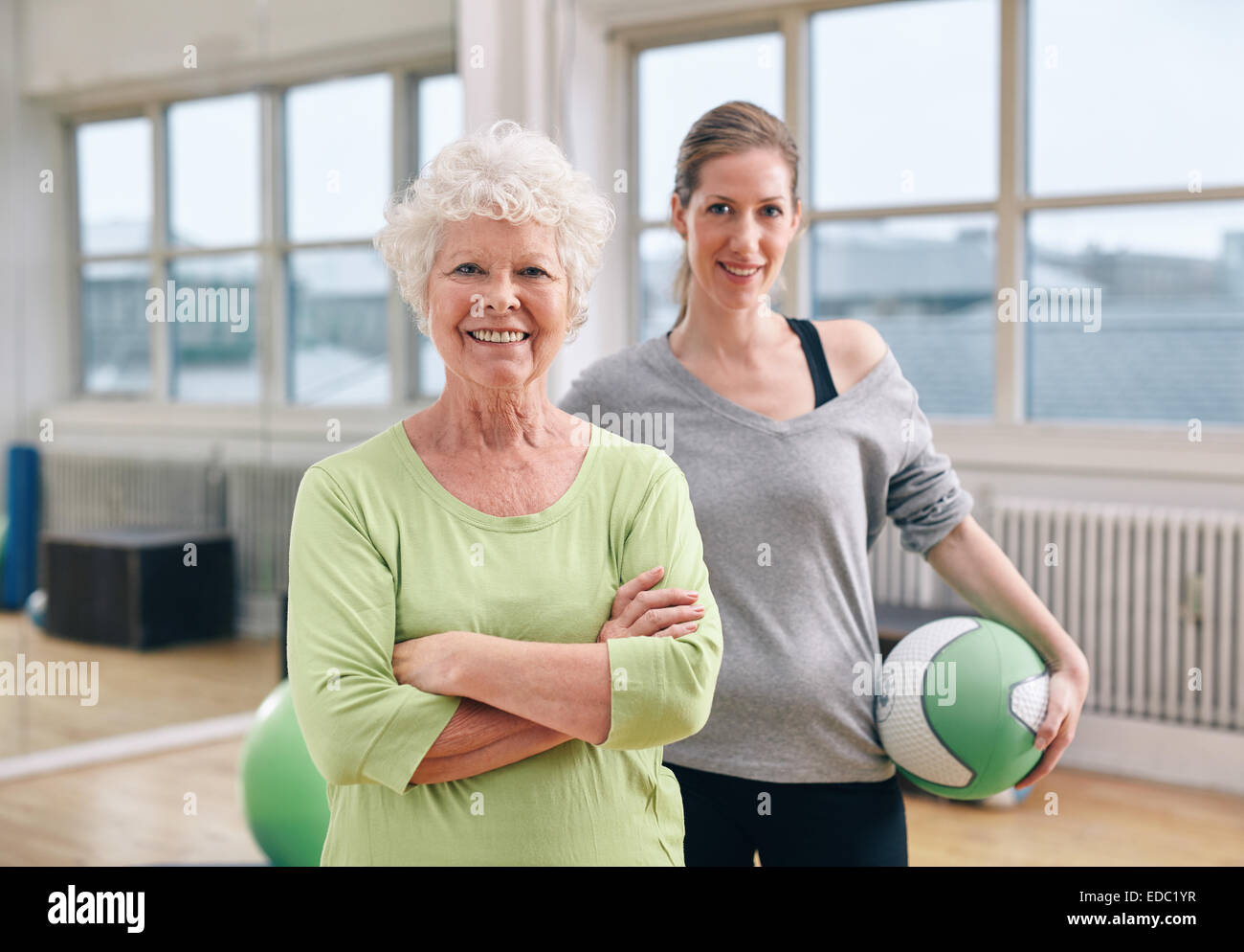 Portrait of happy senior woman standing with her arms crossed and her ...