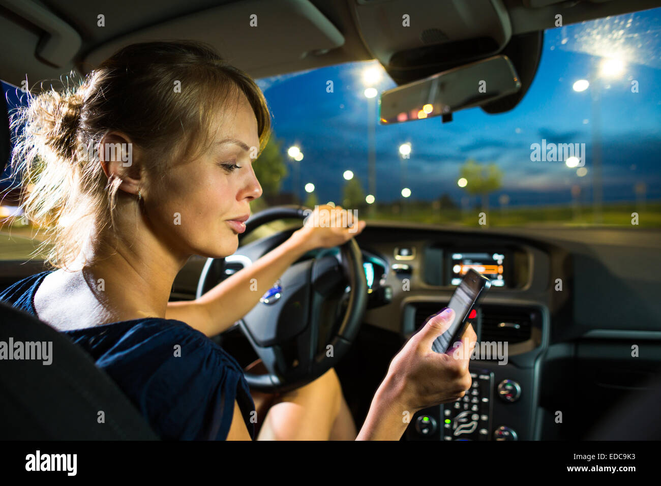 Driving a car at night - pretty, young woman driving her modern car at ...