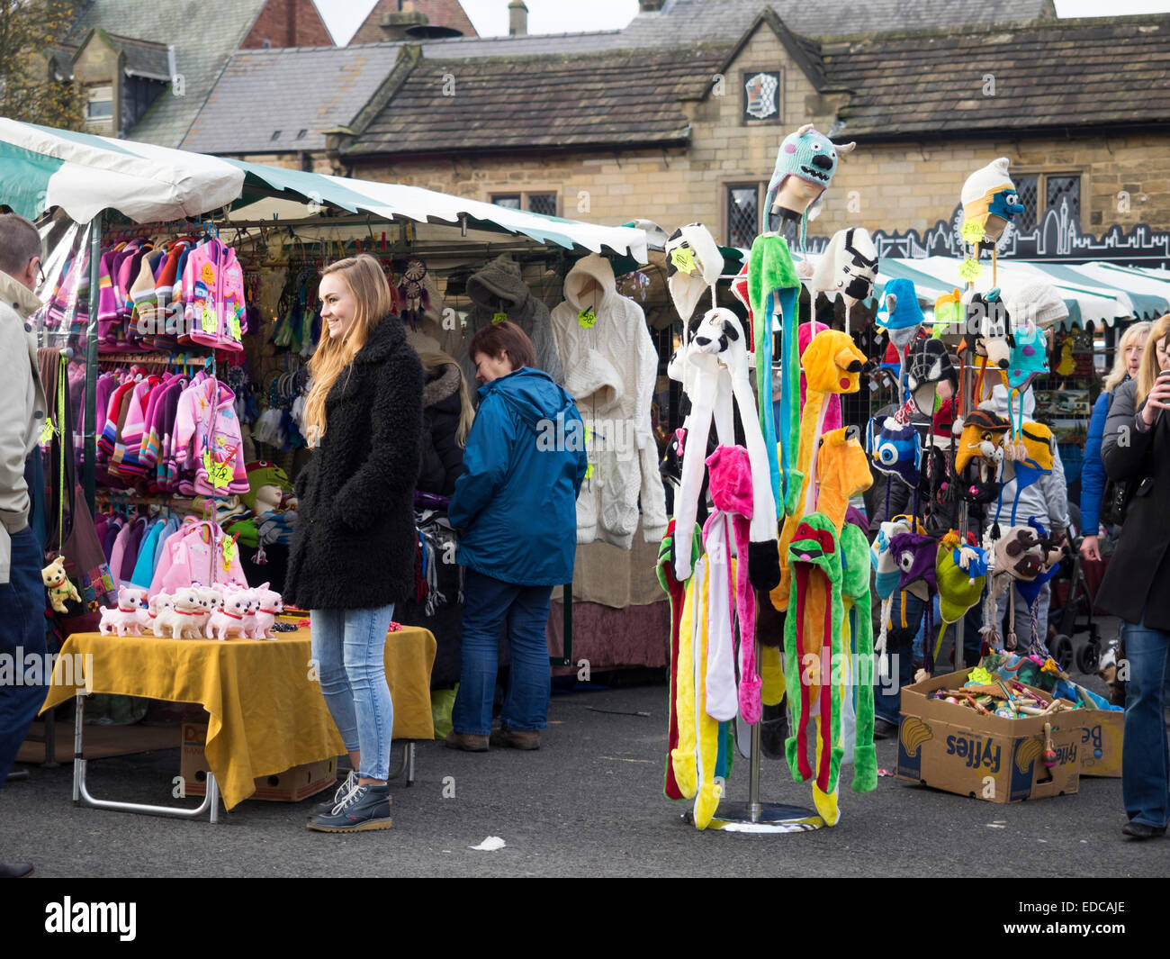 Shoppers looking round Christmas market stall selling hats woolen wear ...