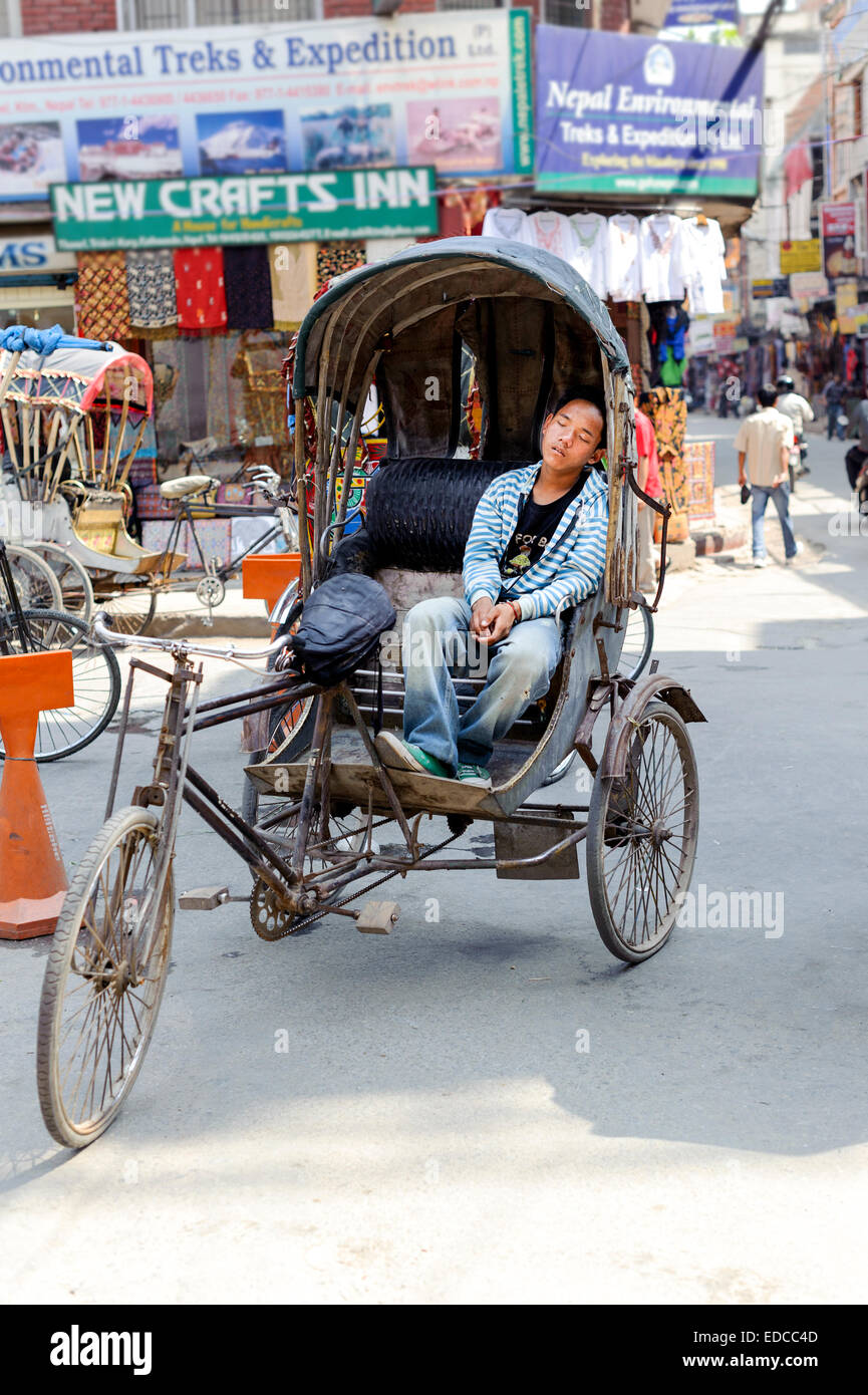 Tired cycle rickshaw driver sleeping on his vehicle at the entrance of ...