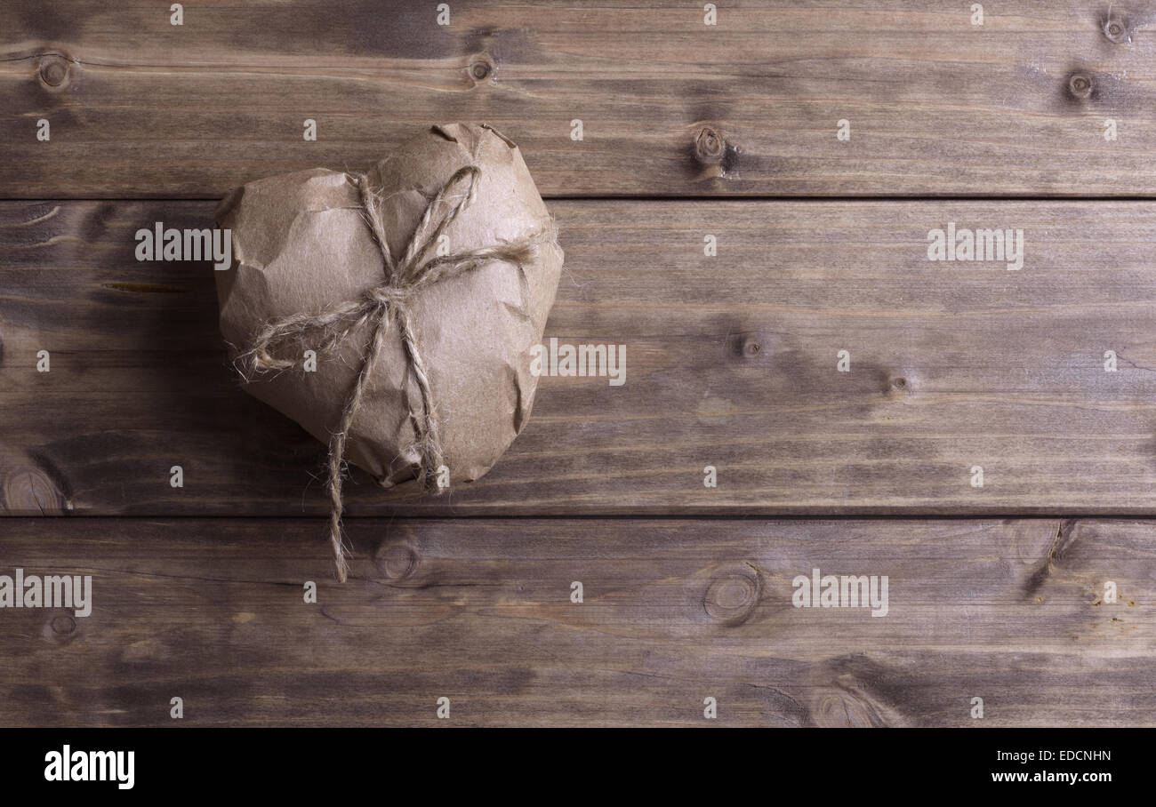 Heart wrapped in brown kraft paper, on wooden background Stock Photo ...