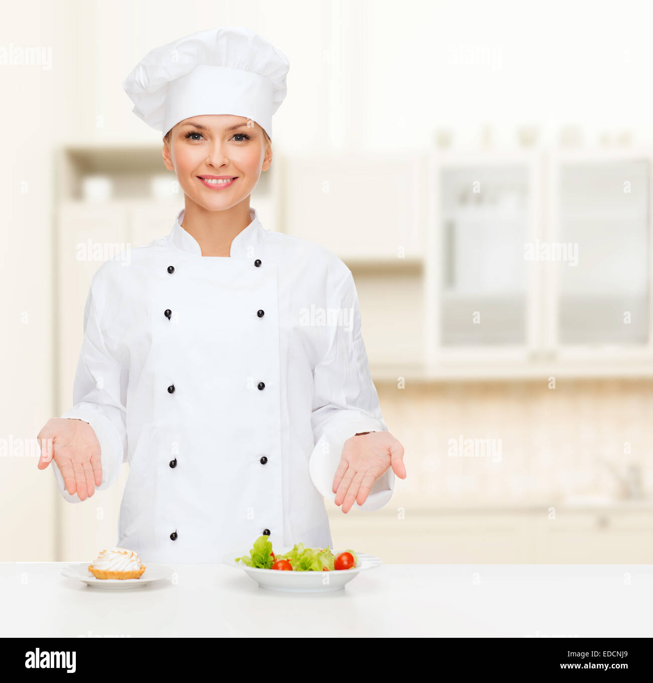 smiling female chef with salad and cake on plates Stock Photo - Alamy