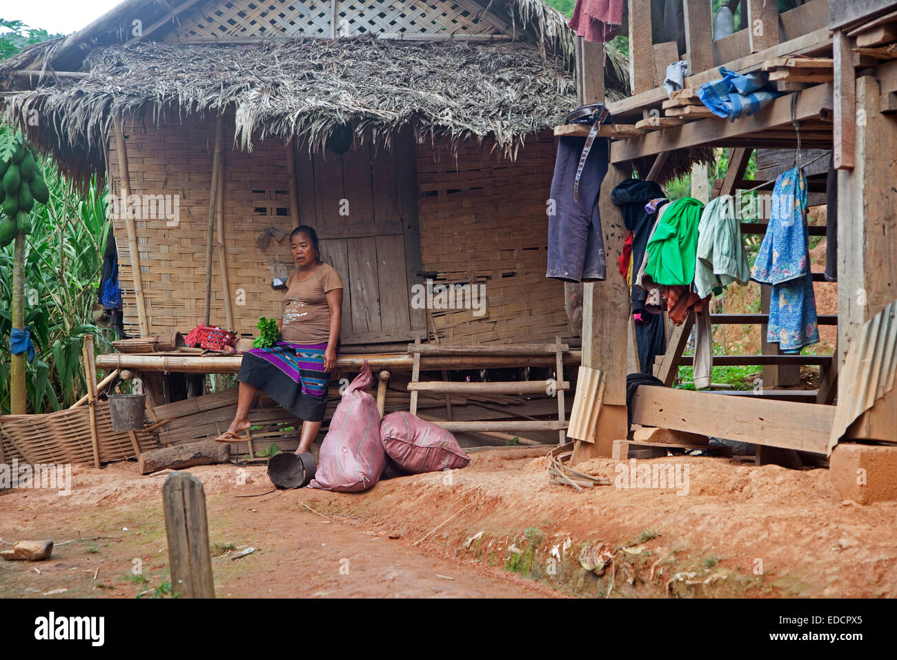 Lao woman of the Khmu / Khamu / Kemu tribe in front of bamboo hut in ...