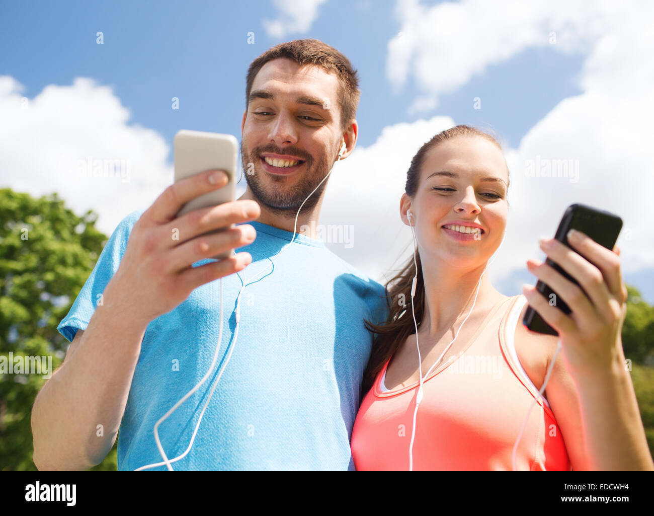 two smiling people with smartphones outdoors Stock Photo - Alamy