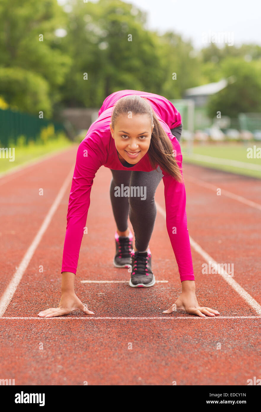 smiling young woman running on track outdoors Stock Photo - Alamy