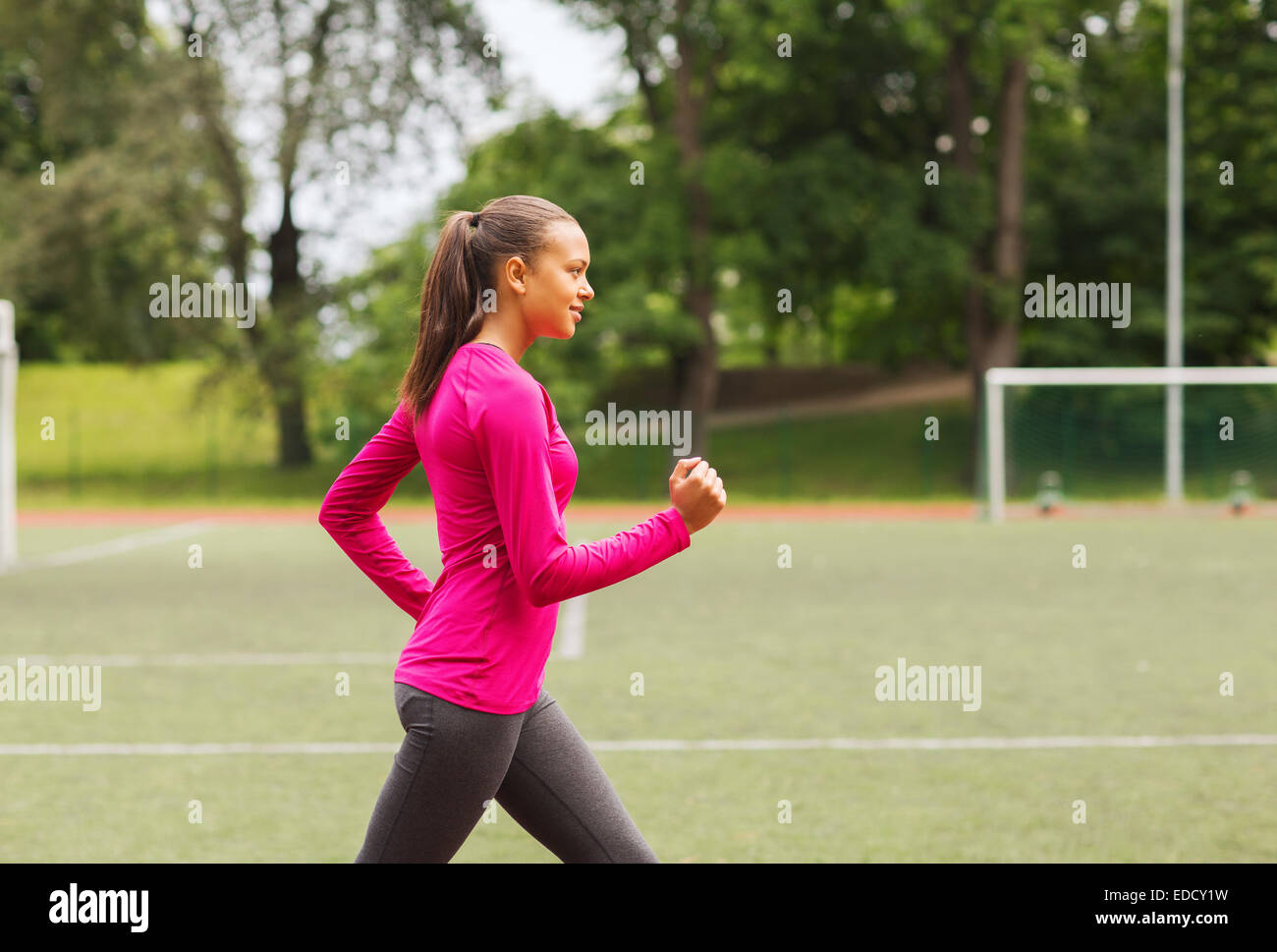 smiling young woman running on track outdoors Stock Photo - Alamy