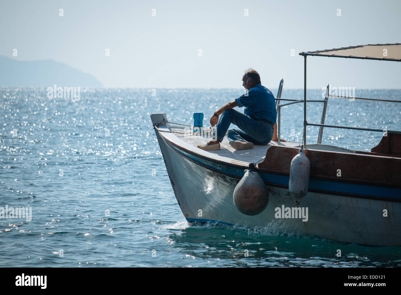 A greek man sitting on a boat looking at the sea, Santorini, Cyclades ...