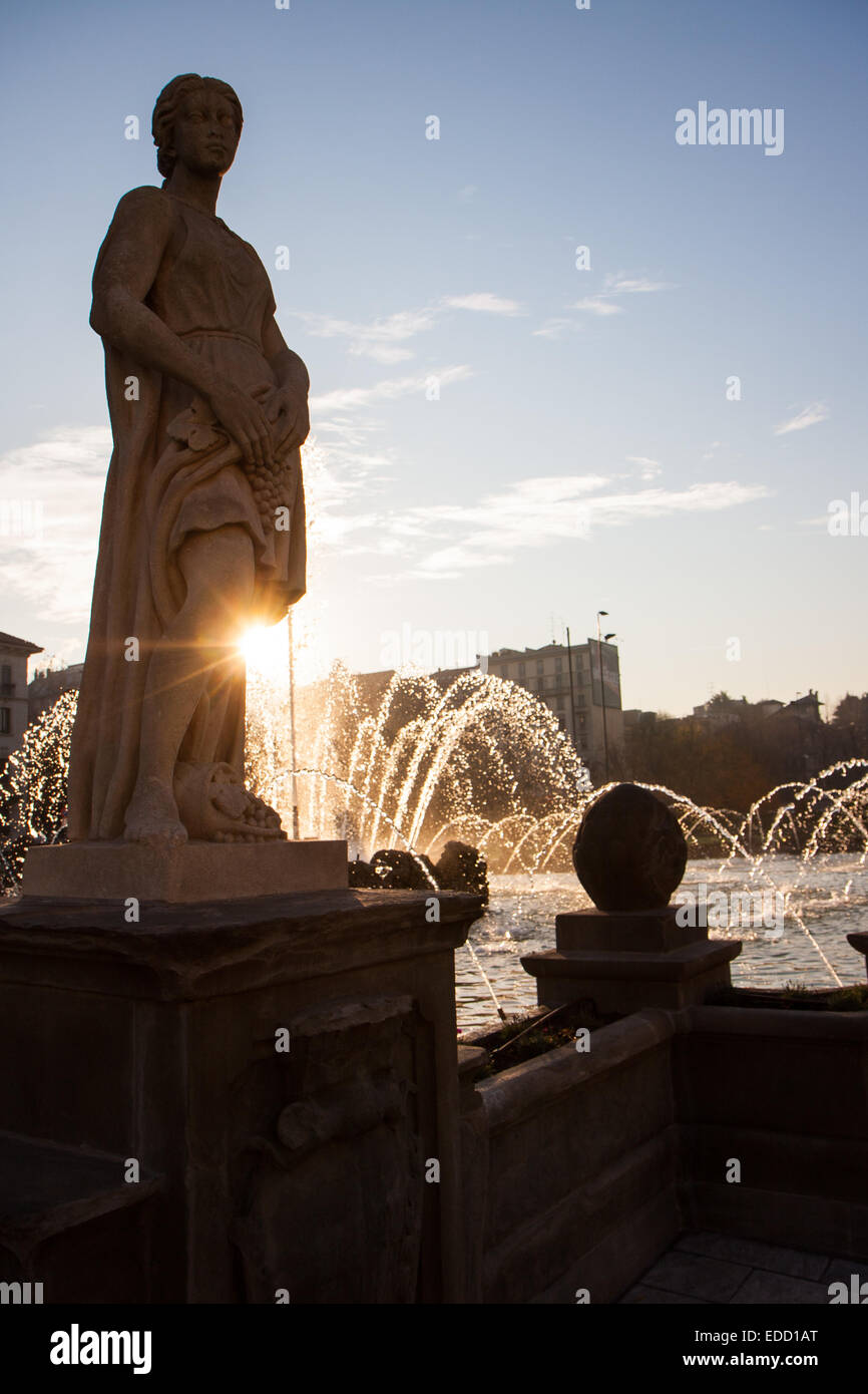 backlit urban fountain with a statue of a woman in the foreground Stock ...
