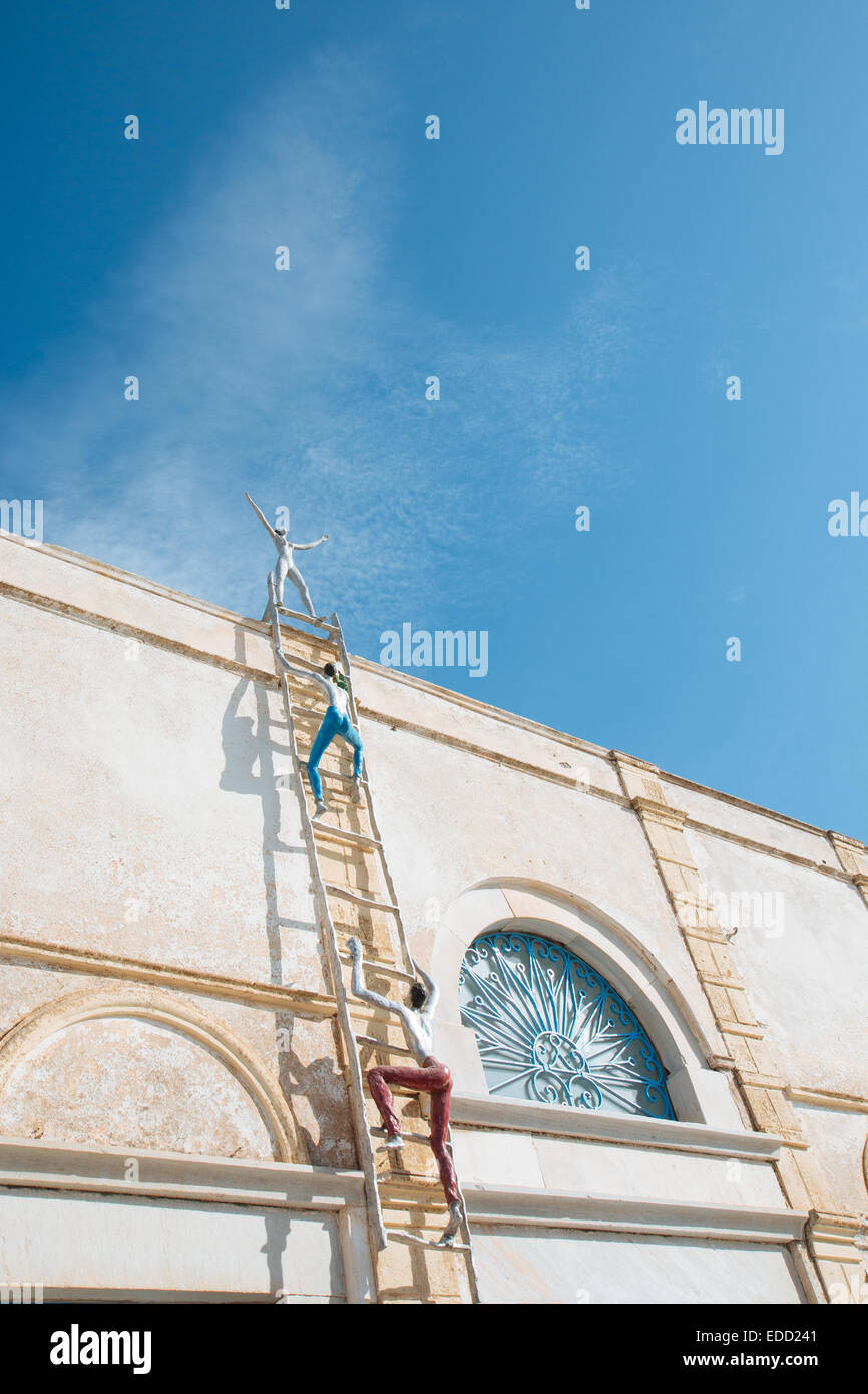 Sculpture of people climbing up a ladder into the blue sky, Oia ...