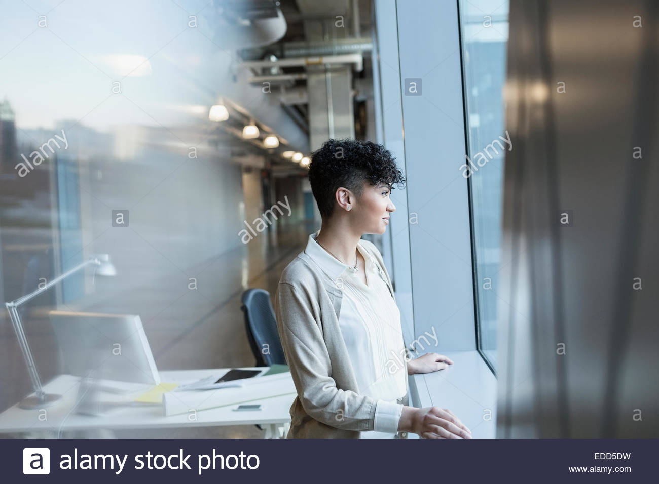Businesswoman looking out office window Stock Photo - Alamy