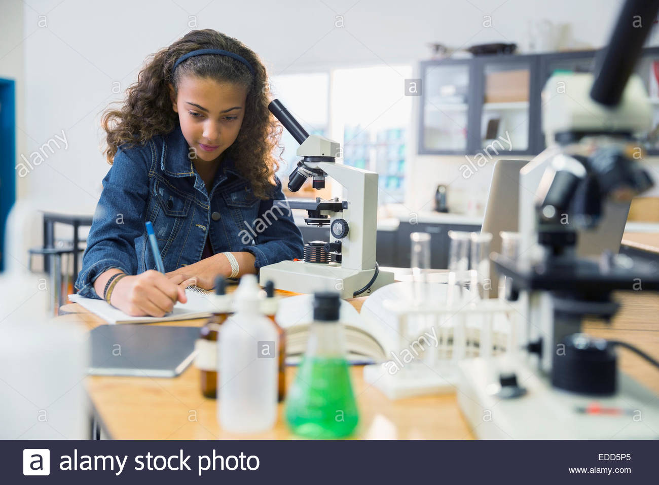 Elementary student at microscope taking notes in laboratory Stock Photo ...