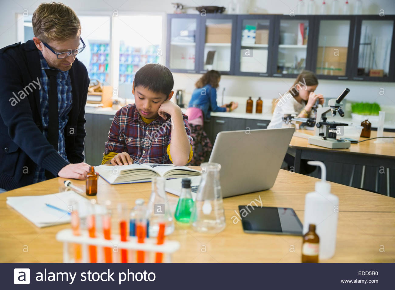 Teacher and elementary student looking at textbook Stock Photo - Alamy
