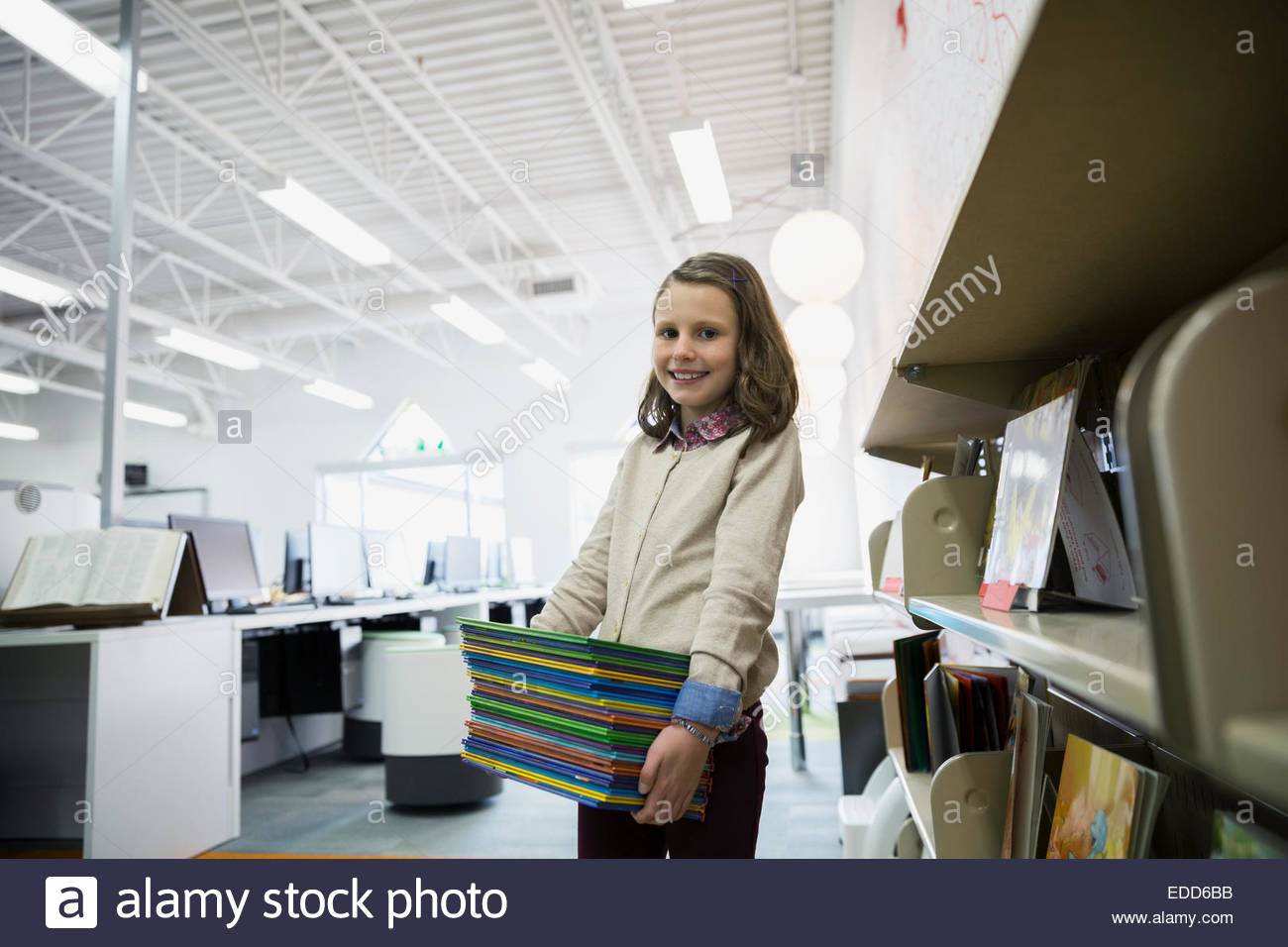 Portrait of elementary student carrying stack of books Stock Photo - Alamy