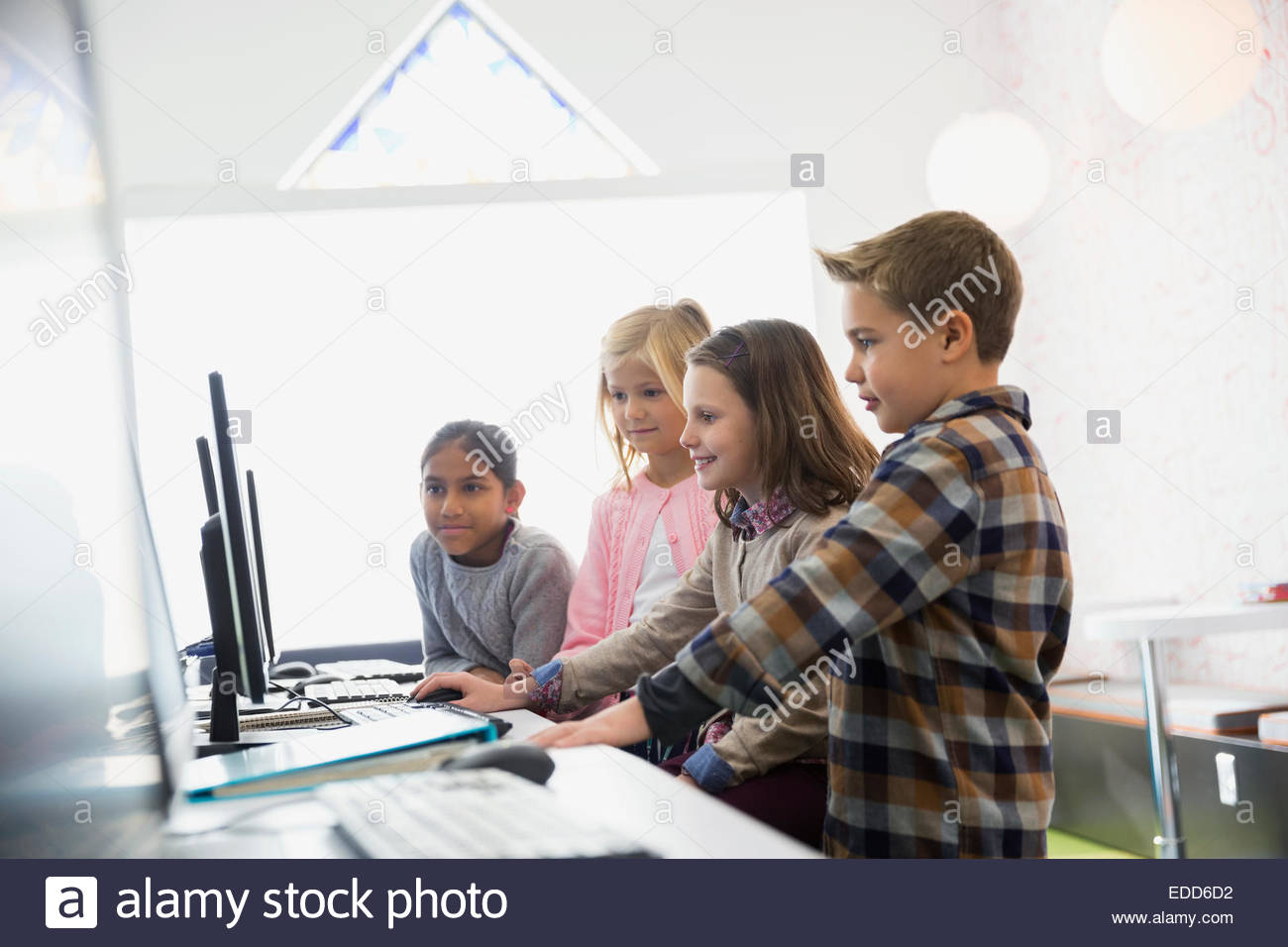 Elementary students using computer in classroom Stock Photo - Alamy