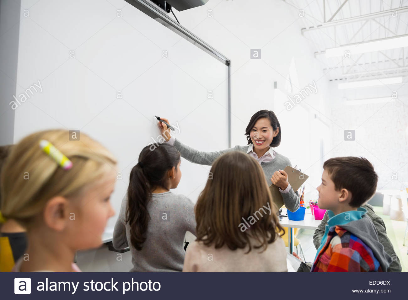 Elementary students watching teacher at whiteboard Stock Photo - Alamy