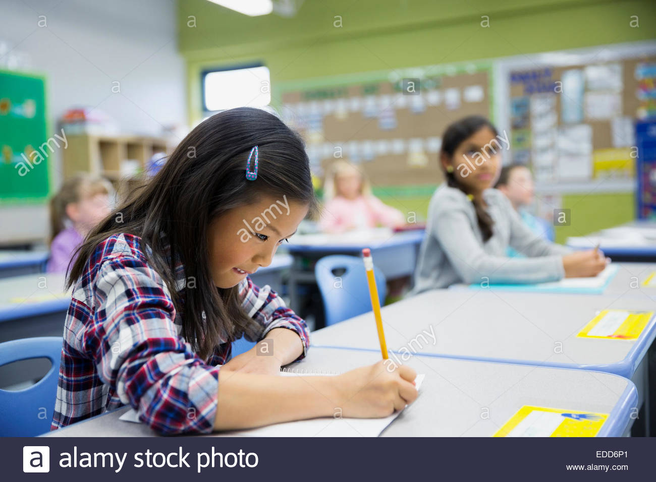 Elementary student writing at desk in classroom Stock Photo - Alamy