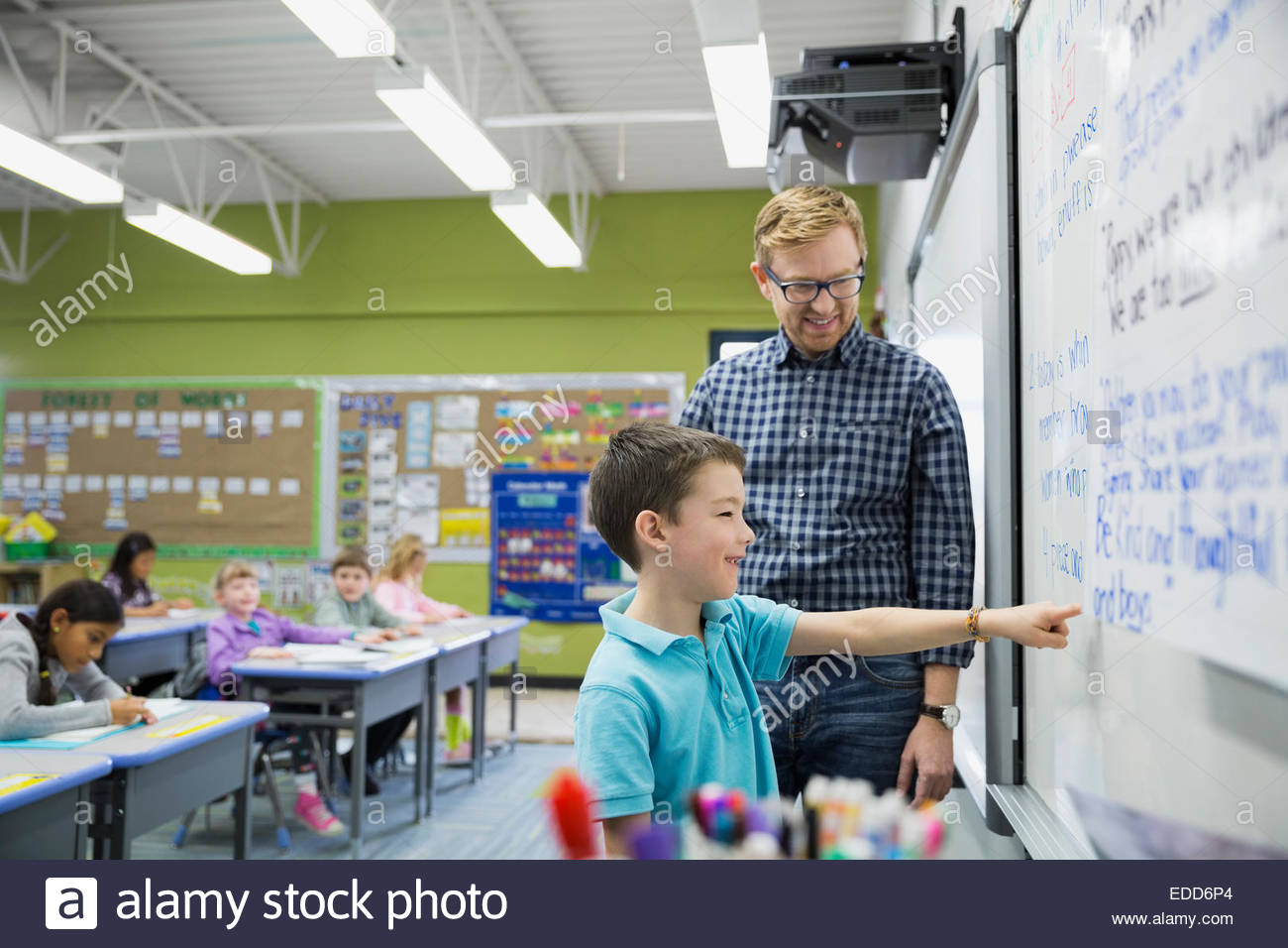Teacher and elementary student at whiteboard in classroom Stock Photo ...