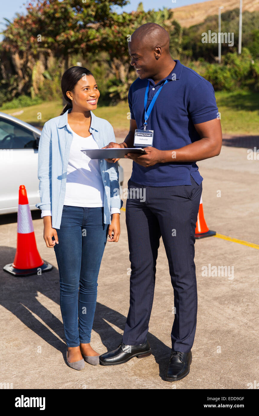 beautiful African student driver with instructor filling forms before ...