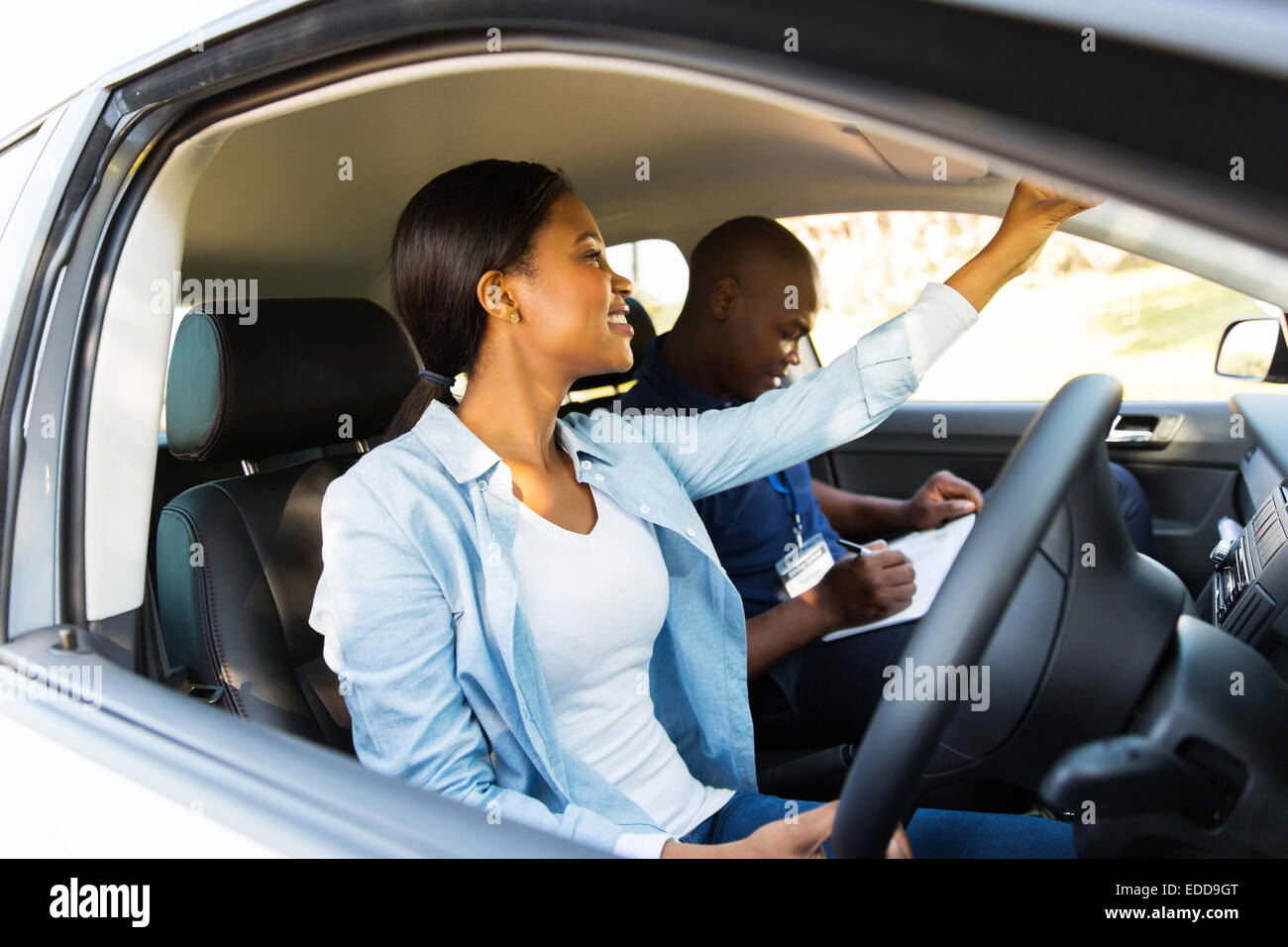 African learner driver adjusting rear view mirror before a driving test ...