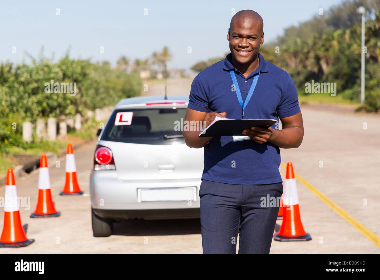 portrait of African American driving instructor writing on clipboard ...