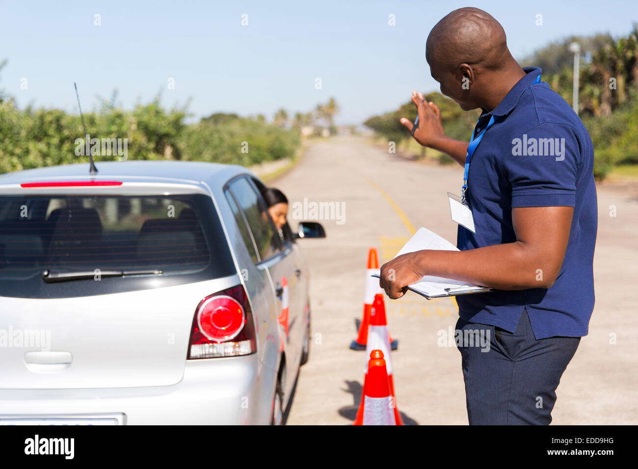 African instructor teaching learner driver to park a car in testing ...