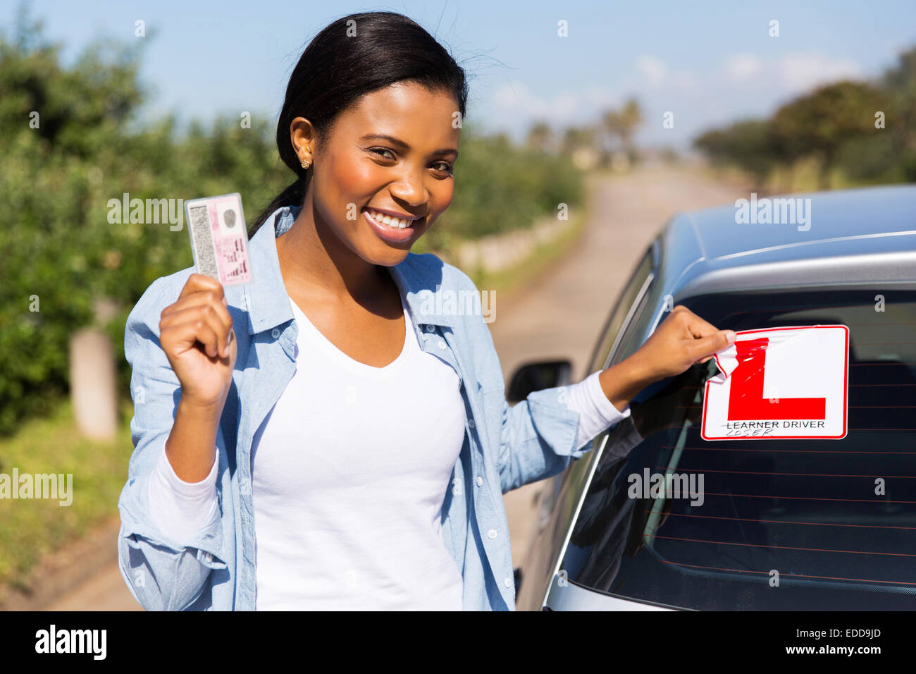 African woman removing learner driver sign after getting her driving ...