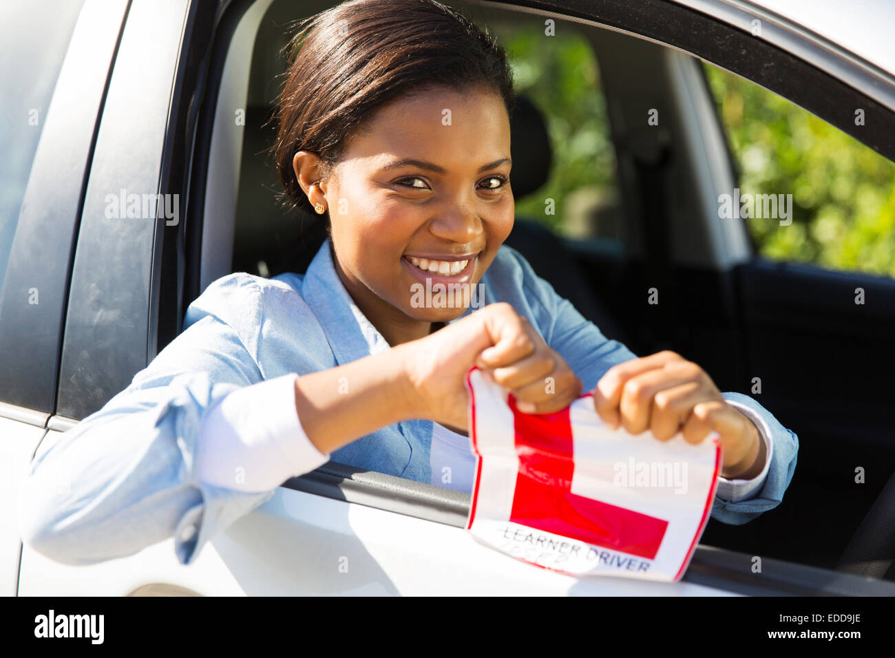 African girl sitting in a car tearing a L sign after having her driver ...