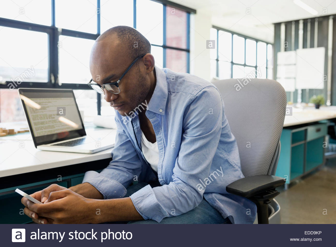Businessman texting at desk in office Stock Photo - Alamy