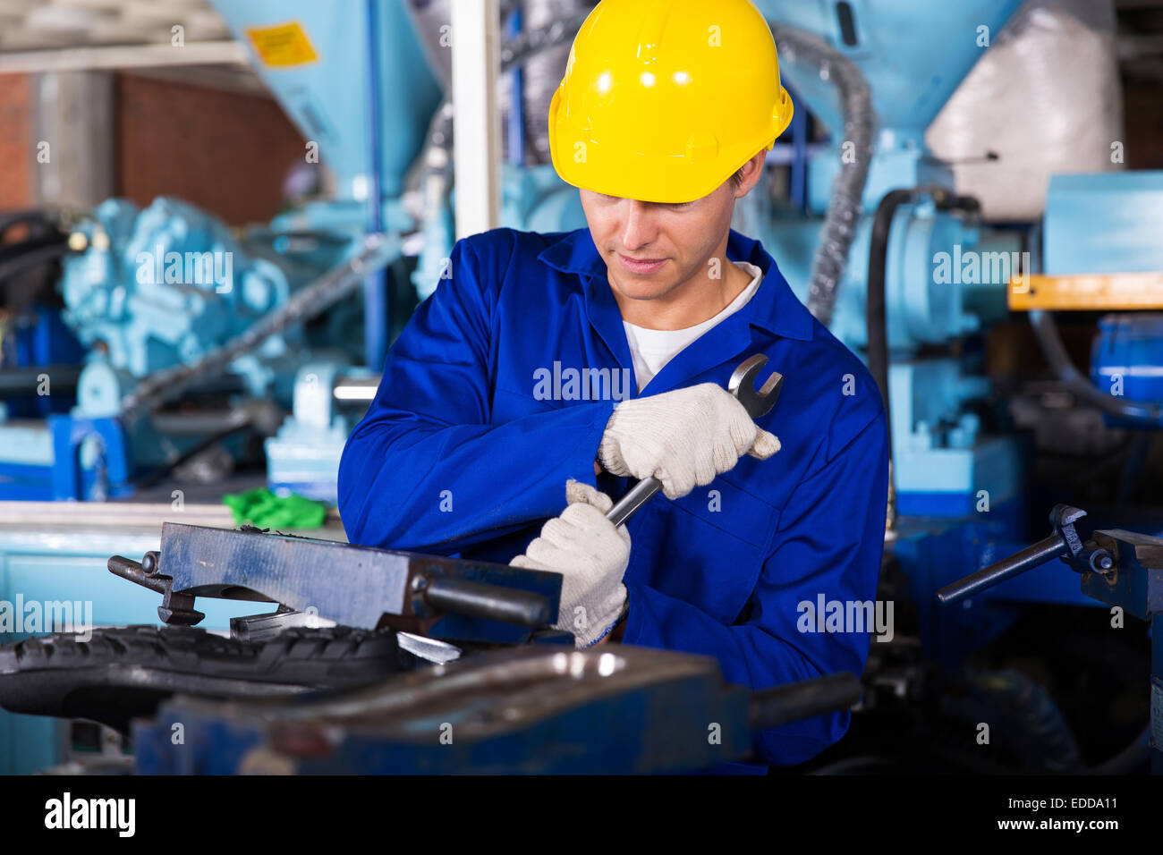 skilled factory mechanic using spanner fasten gumboot making machine ...