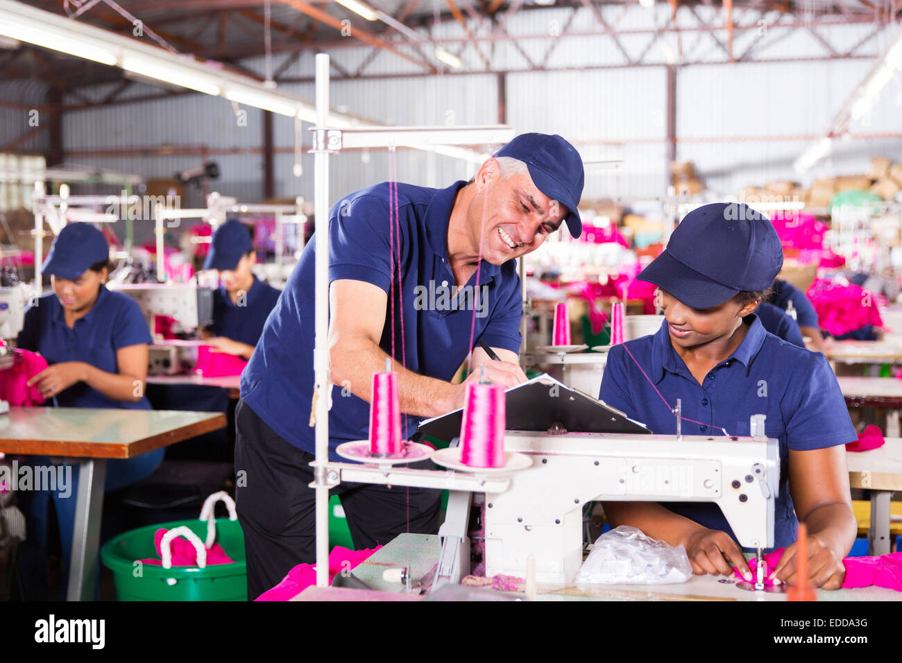 senior textile factory supervisor taking score from machinist Stock Photo - Alamy