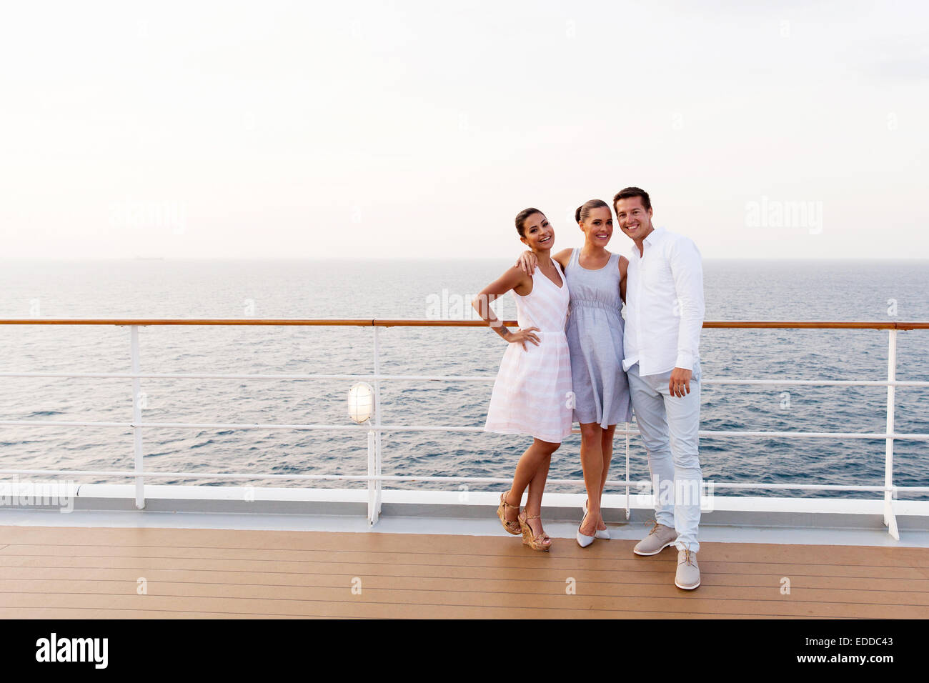 full length portrait of three friends standing on cruise ship deck ...
