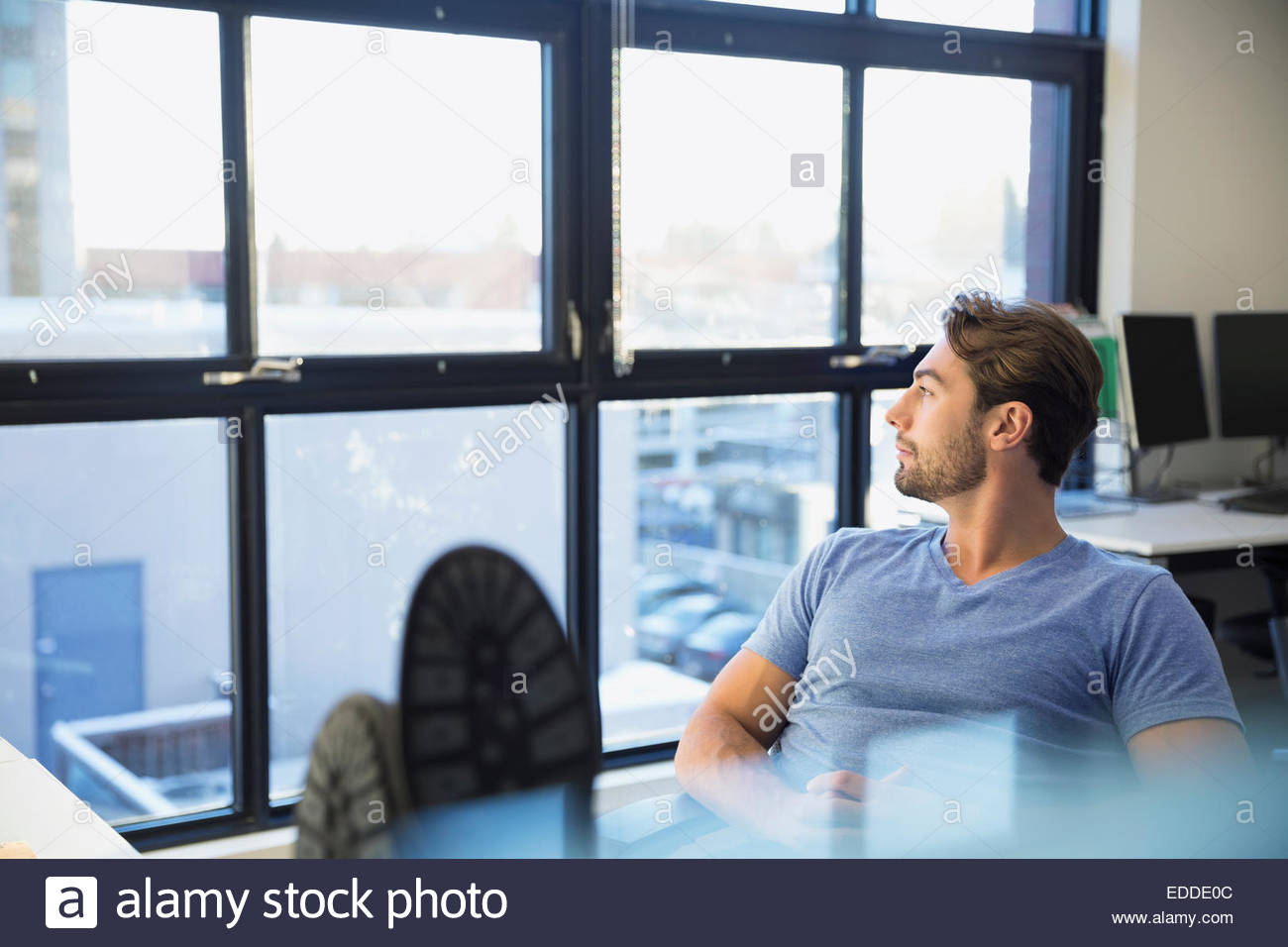 Pensive businessman with feet up looking out window Stock Photo - Alamy