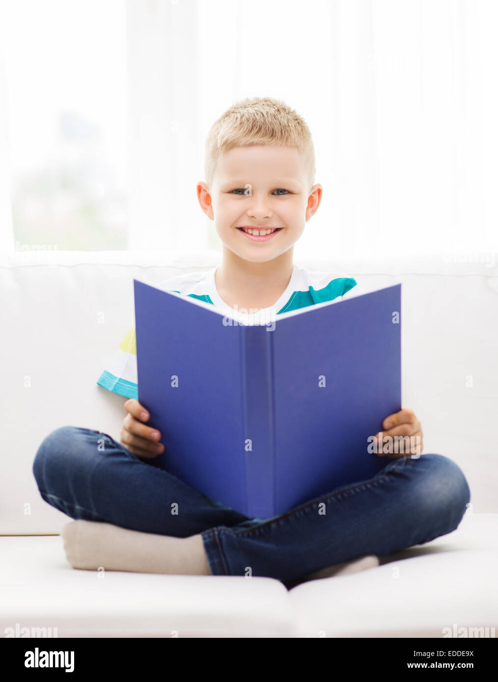 smiling little boy reading book on couch Stock Photo - Alamy